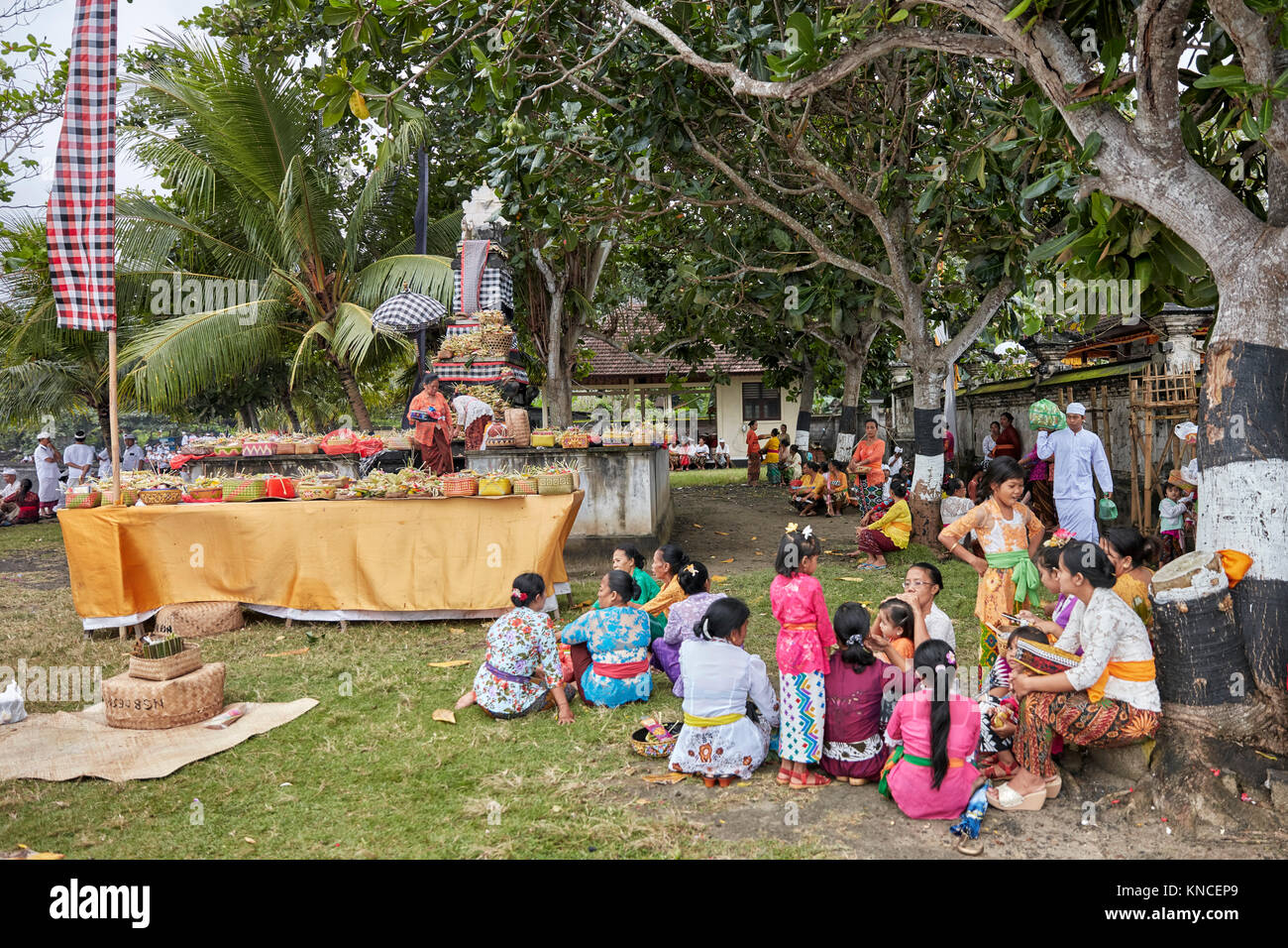 People wearing traditional Balinese clothing sit near altar of local ...