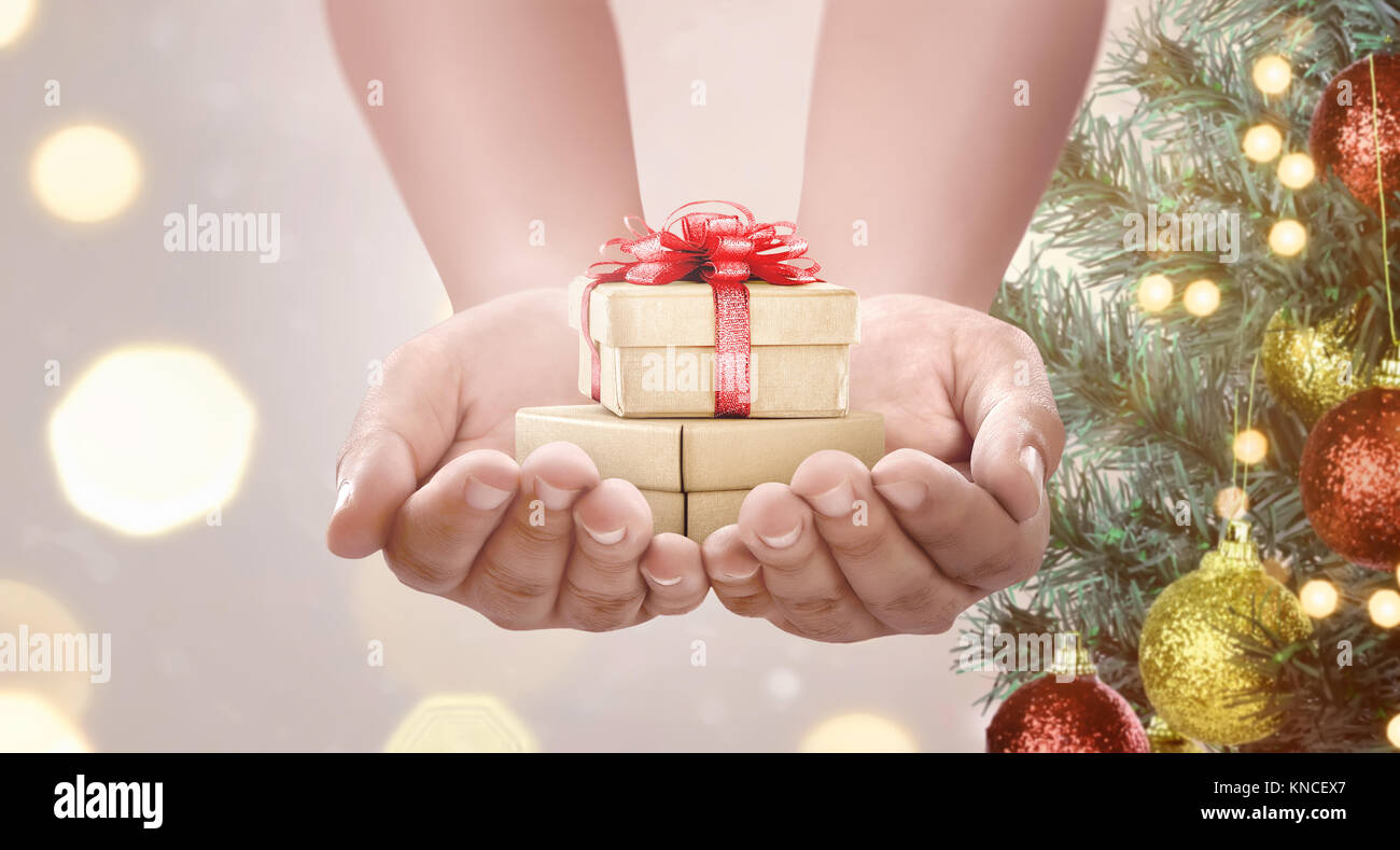 Human hand holding gift box with christmas tree decoration over blurred ...
