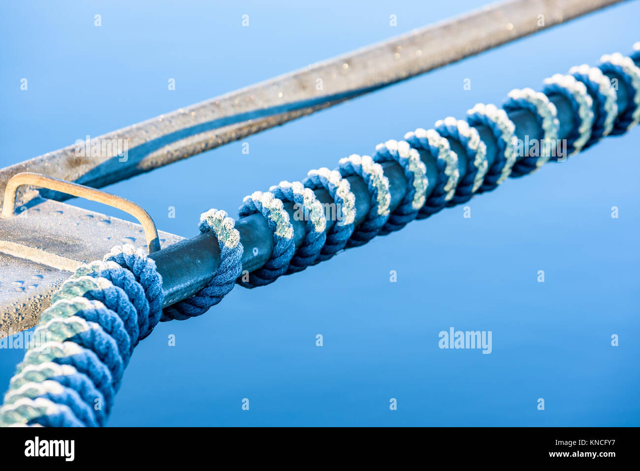 Coiled and twisted rope around a metal rod at a marina on a cold ...