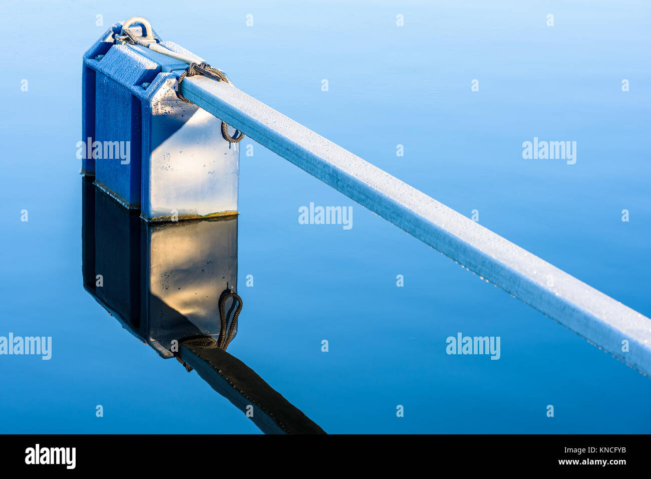 Black mooring buoy at the end of a metal rod at a marina on a cold ...