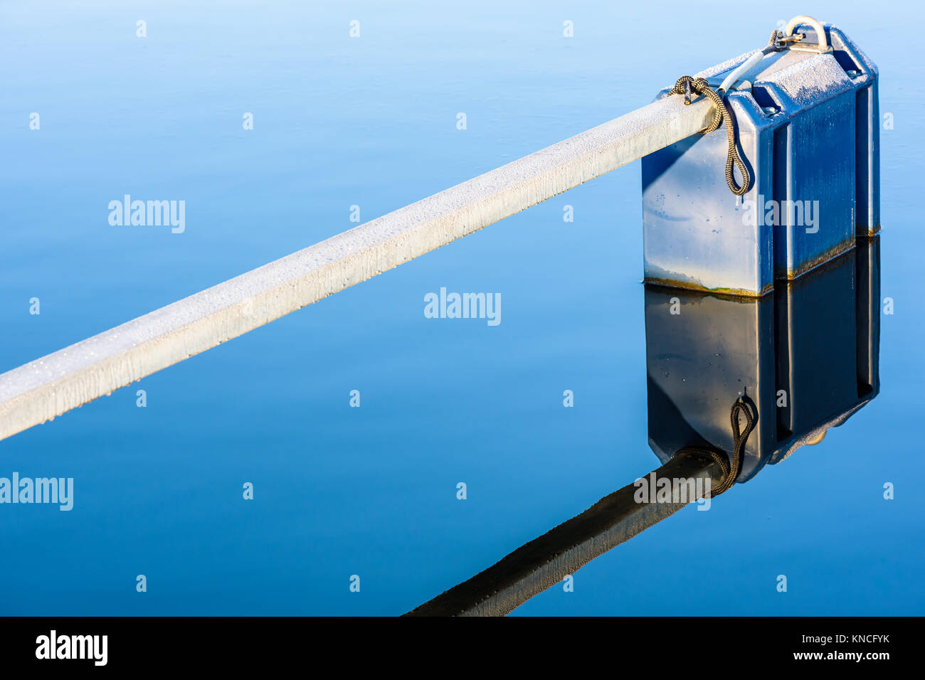 Black mooring buoy at the end of a metal rod at a marina on a cold ...