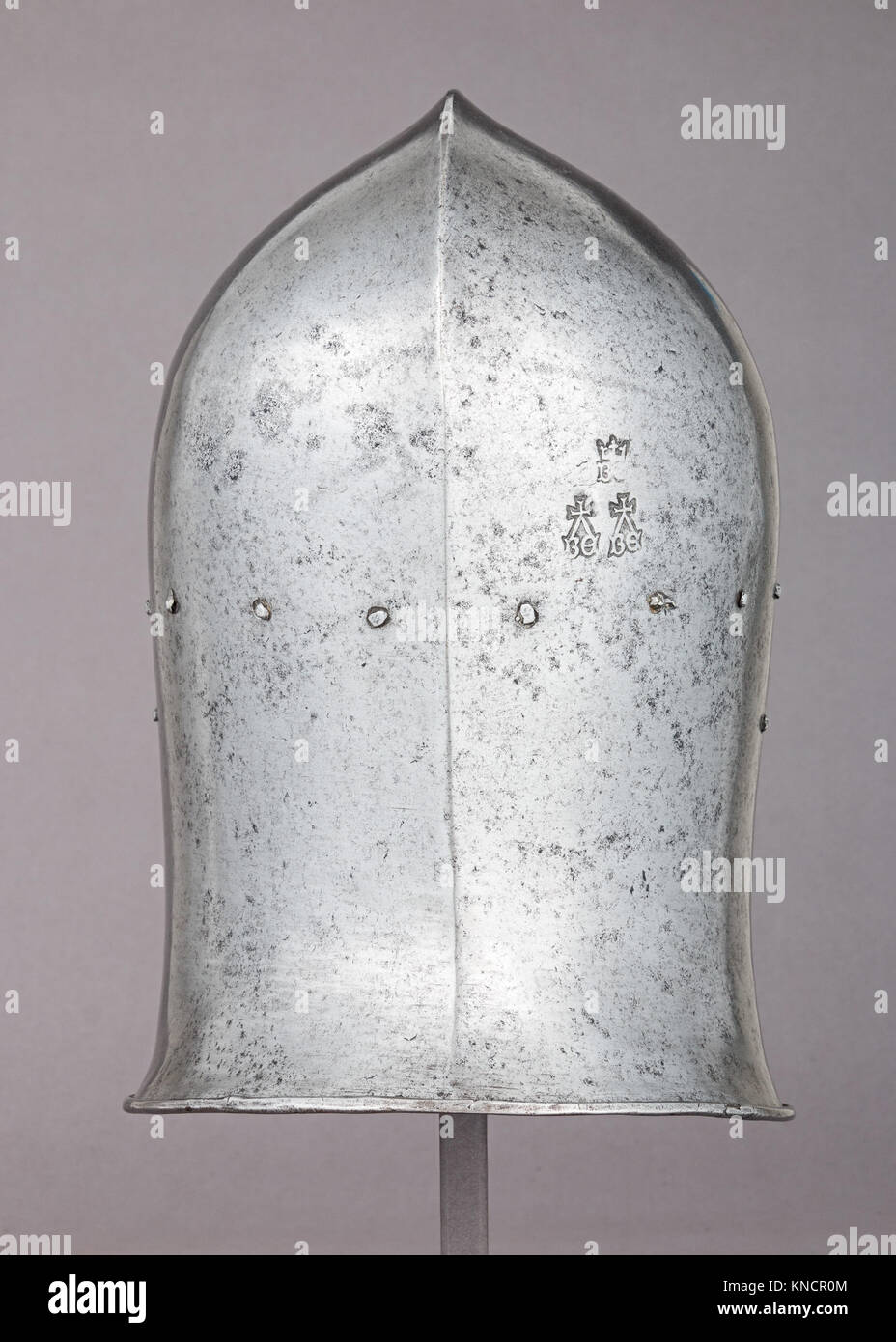 This barbute helmet, characteristic of medieval armor, reflects the ...