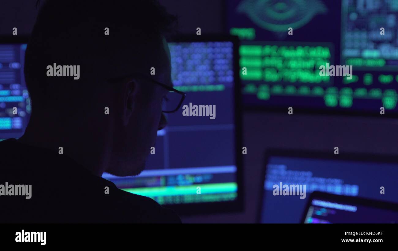 Male hacker working on a computer in a dark office room Stock Photo - Alamy