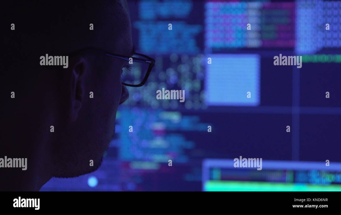 Male hacker working on a computer in a dark office room Stock Photo - Alamy
