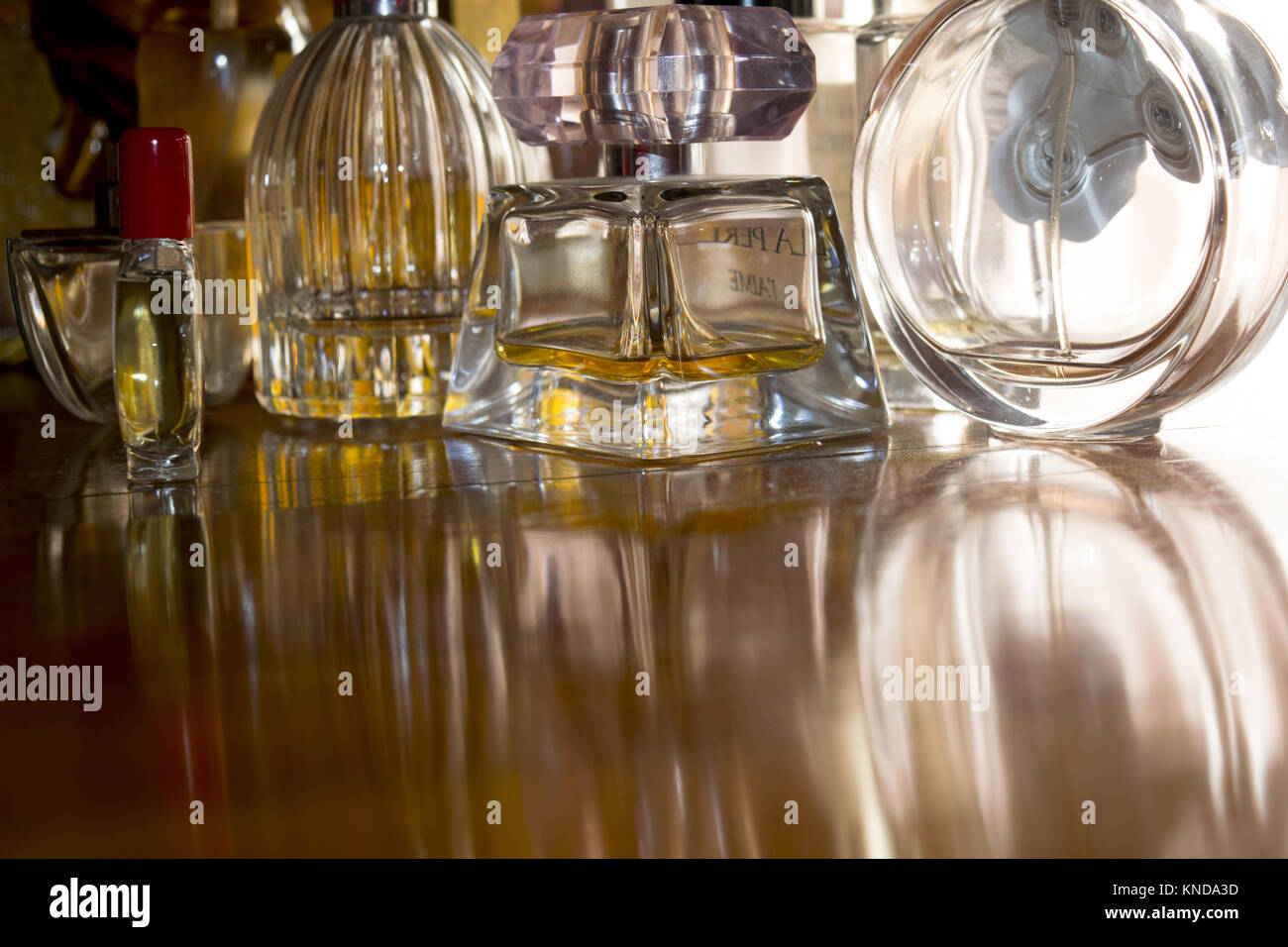 perfume bottles in back-lit on a wooden background and reflections of ...