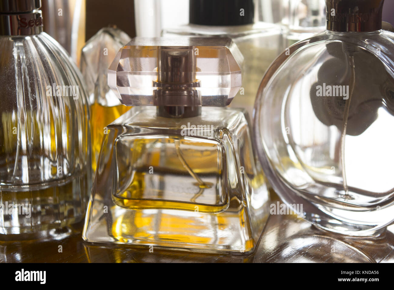perfume bottles in back-lit on a wooden background and reflections of ...
