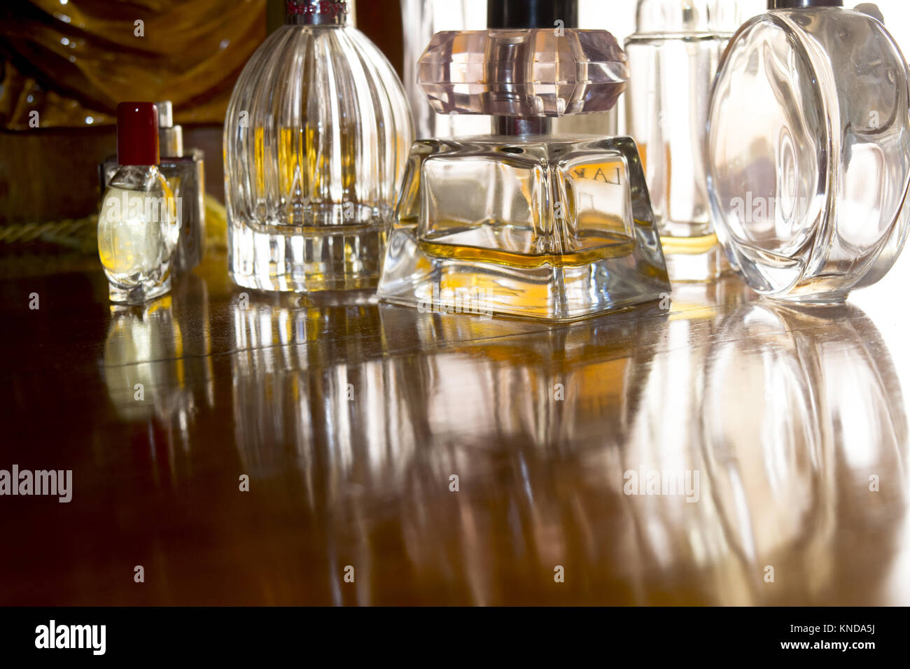 perfume bottles in back-lit on a wooden background and reflections of ...