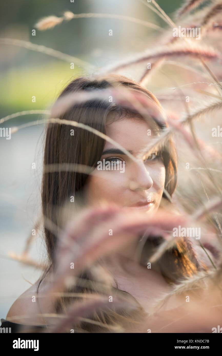 Serious young woman hiding behind the plants Stock Photo - Alamy