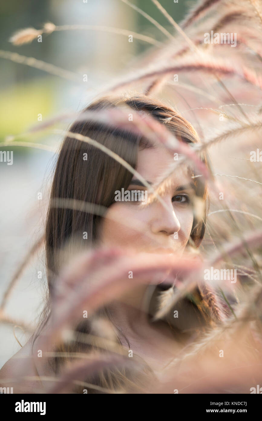 Serious young woman hiding behind the plants Stock Photo - Alamy