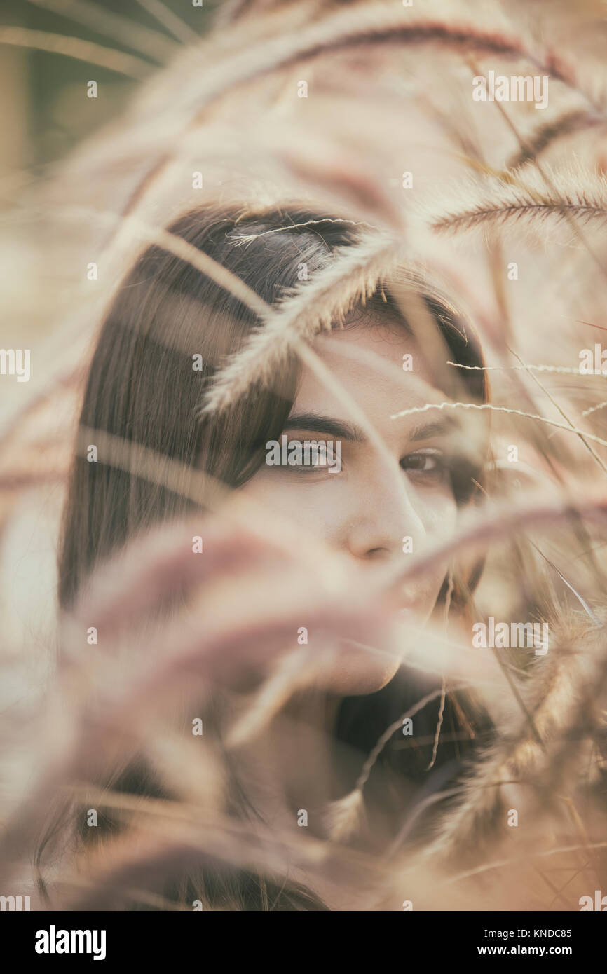 Serious young woman hiding behind the plants Stock Photo - Alamy