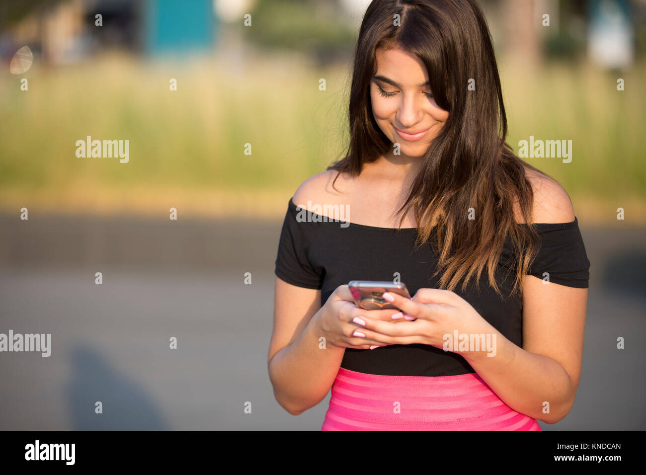 beautiful young woman sending a text message on amobile phone outdoors ...