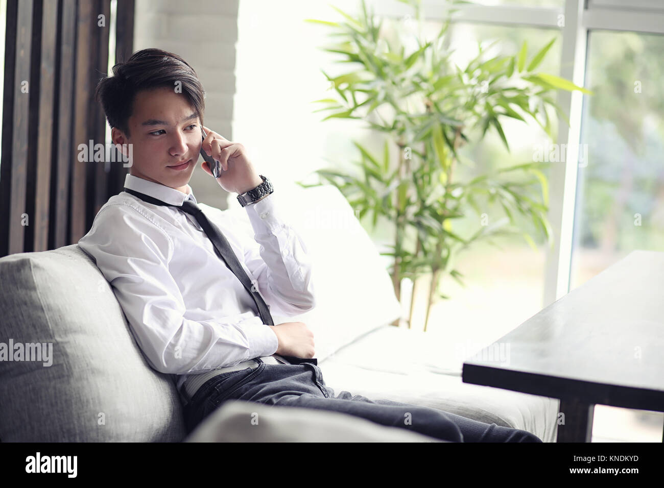 A young Asian businessman is waiting for a partner in a cafe. Bu Stock ...
