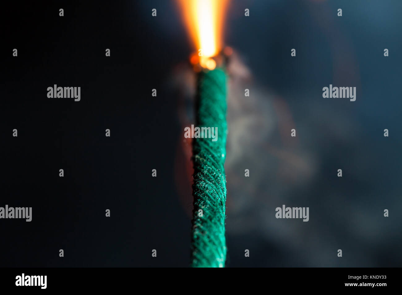 Close-up of burning fuse with sparks and lot of grey smoke on black ...