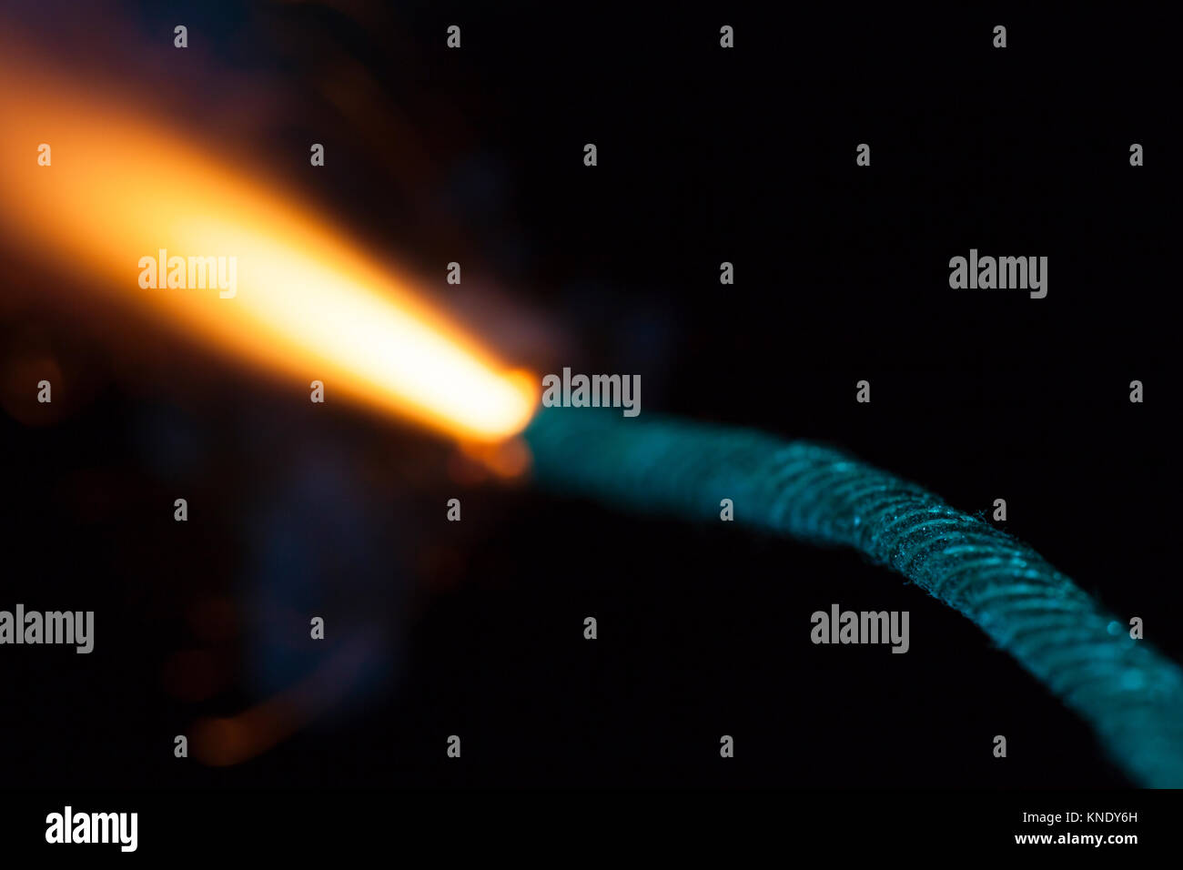 Close-up of burning fuse with sparks and blue smoke on black background ...