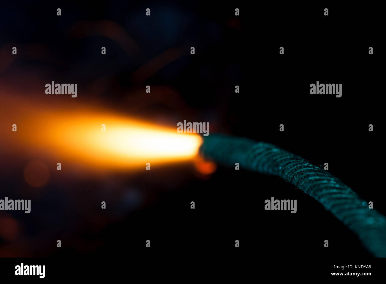 Close-up of burning fuse with sparks and blue smoke on black background ...