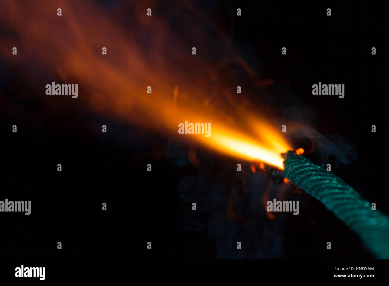 Close-up of burning fuse with sparks and blue smoke on black background ...