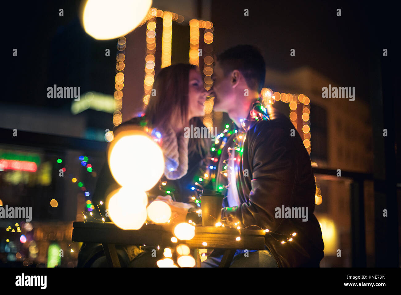 Young couple kissing and hugging outdoor in night street at christmas ...