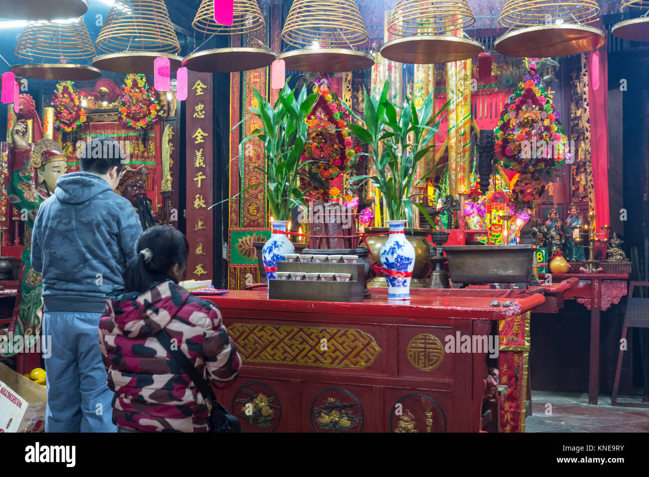 two faithful as they pray before the altar inside the Man Mo temple in ...