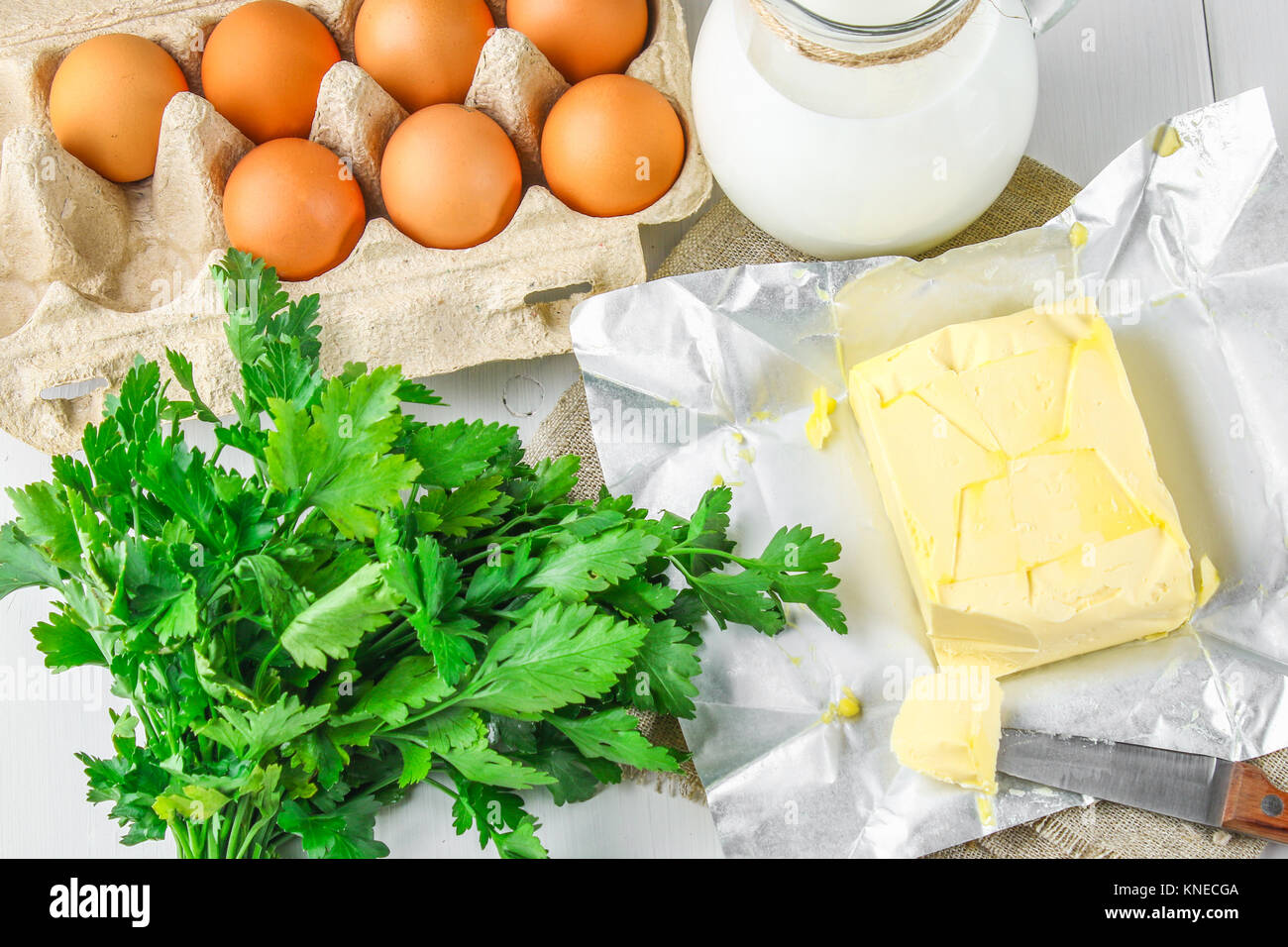 A bar of butter is cut into pieces on a wooden board with a knife ...