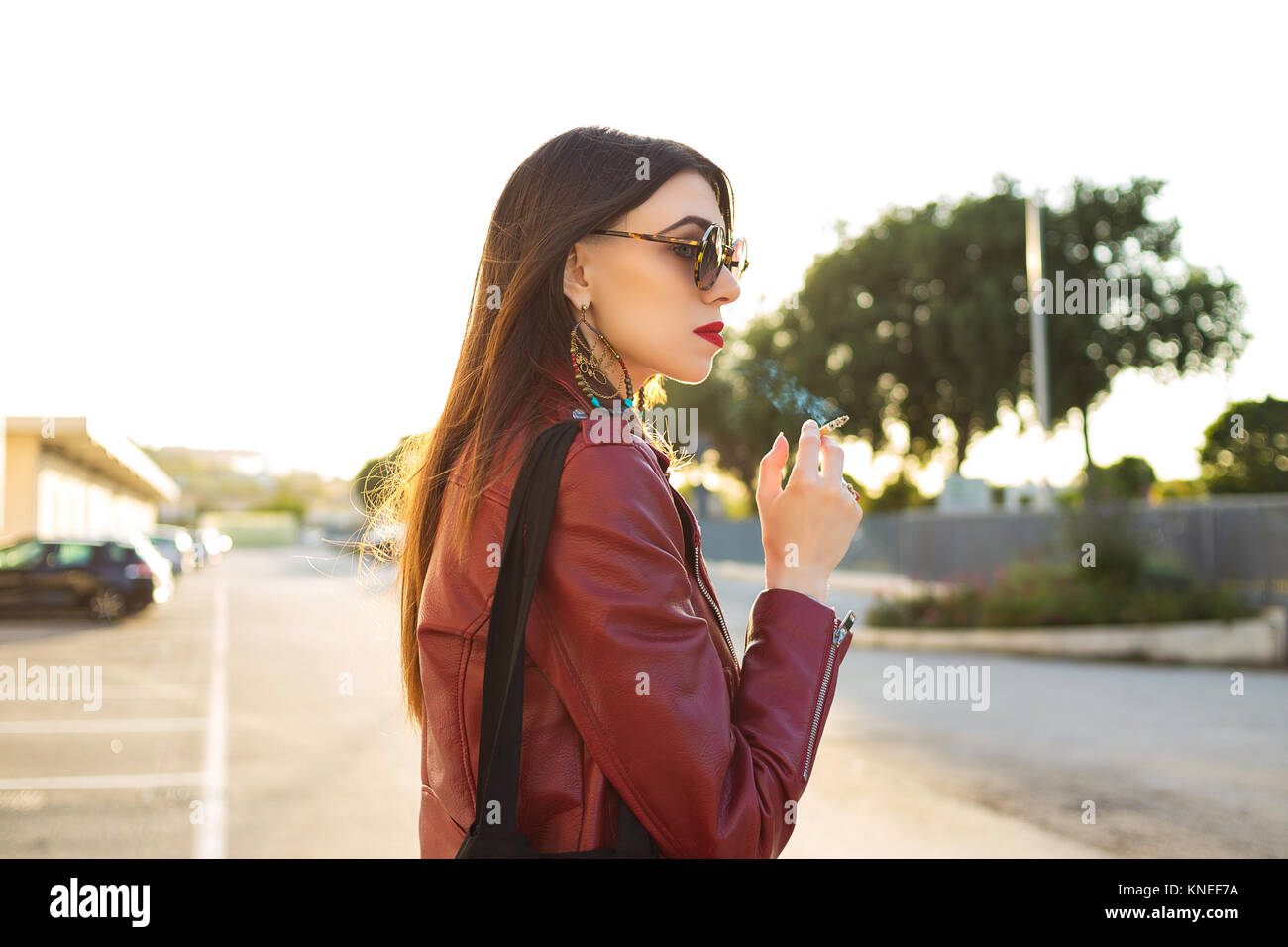 Portrait of a woman standing in street smoking a cigarette Stock Photo ...