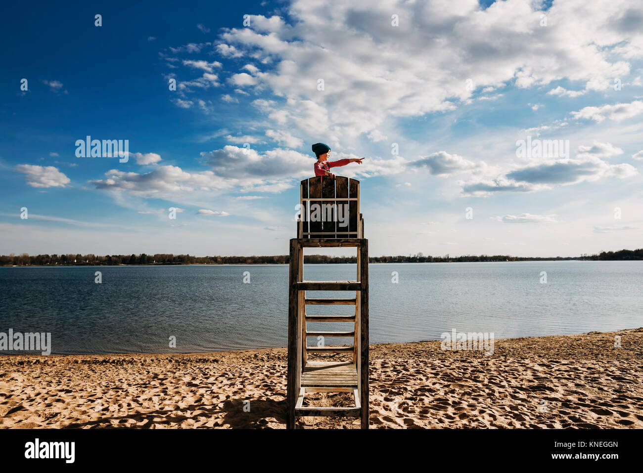 Girl standing on a lifeguard chair by a lake pointing Stock Photo - Alamy