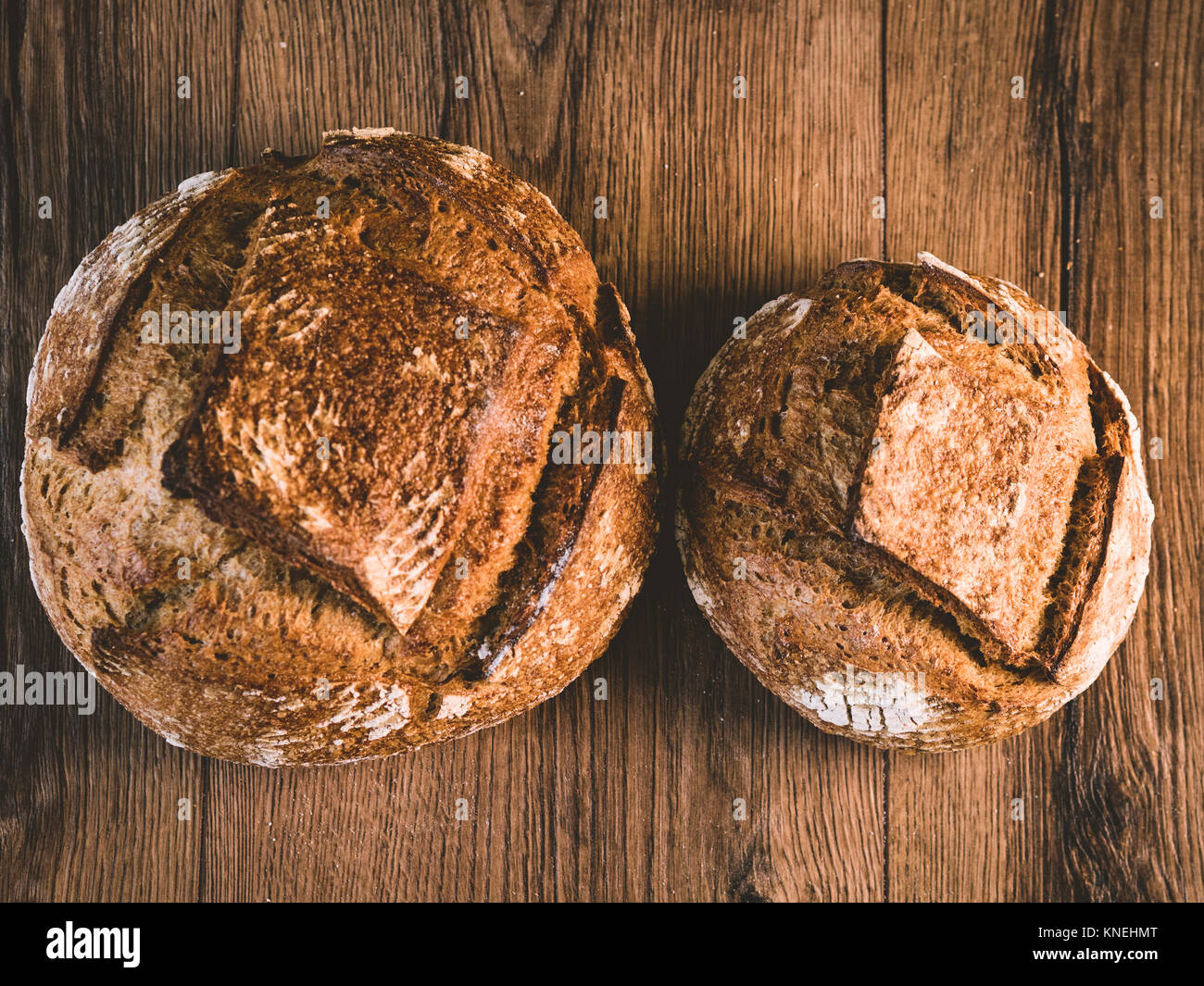 Two loaves of bread next to each other on a wooden table Stock Photo ...