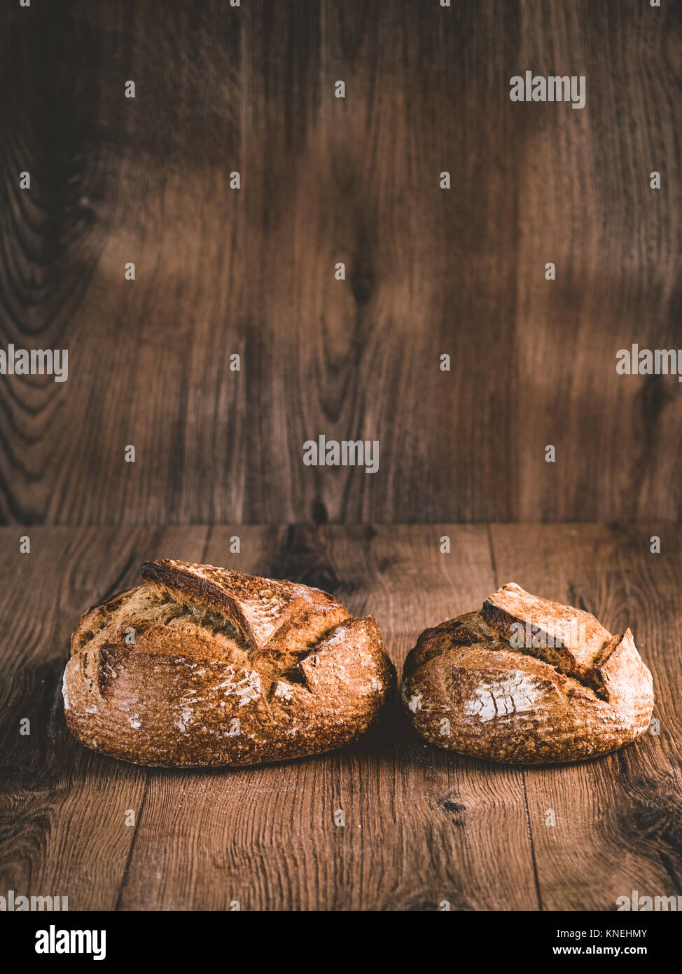 Two loaves of bread next to each other on a wooden table Stock Photo ...