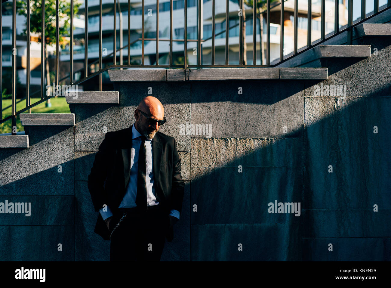 Portrait of mature businessman outdoors, standing beside steps, pensive ...