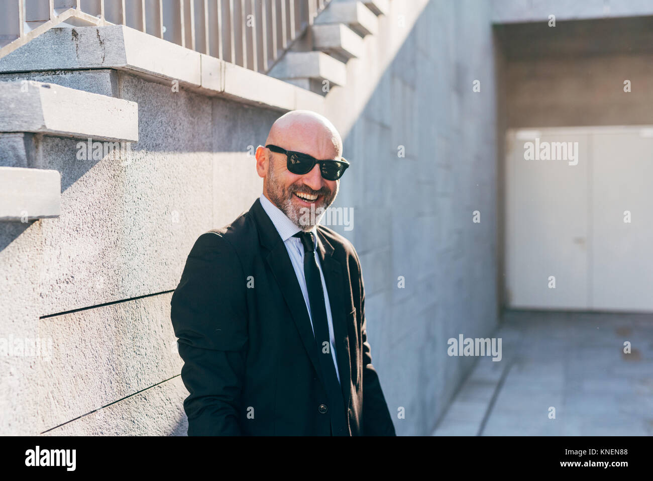 Portrait of mature businessman outdoors, standing beside steps, smiling ...