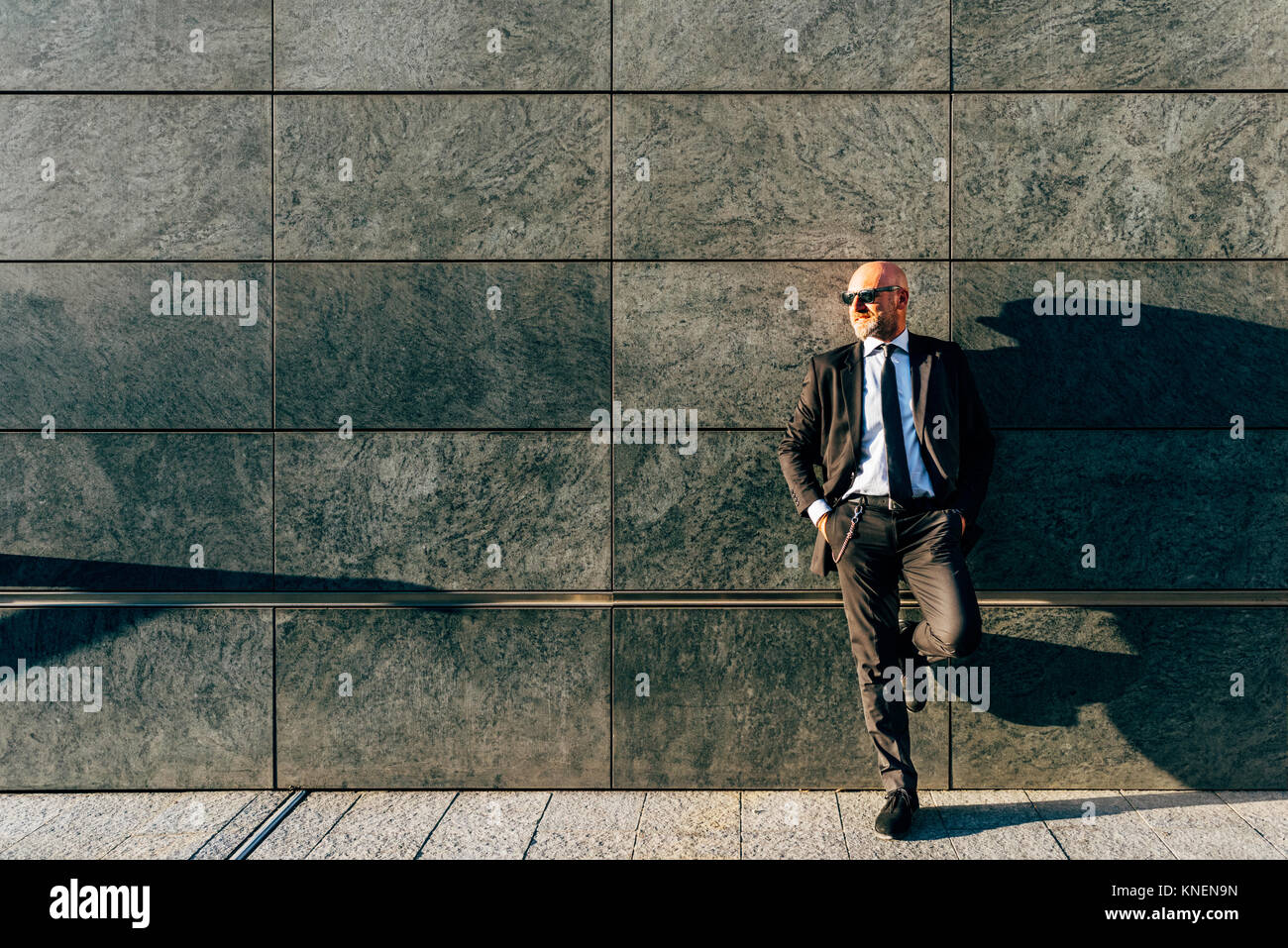Mature businessman outdoors, leaning against wall Stock Photo - Alamy