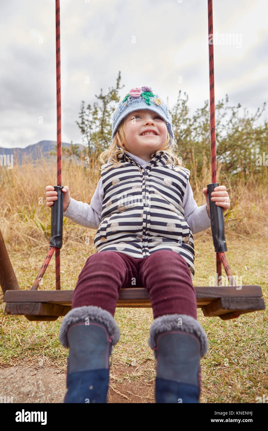 Girl sitting on swing in rural setting Stock Photo - Alamy