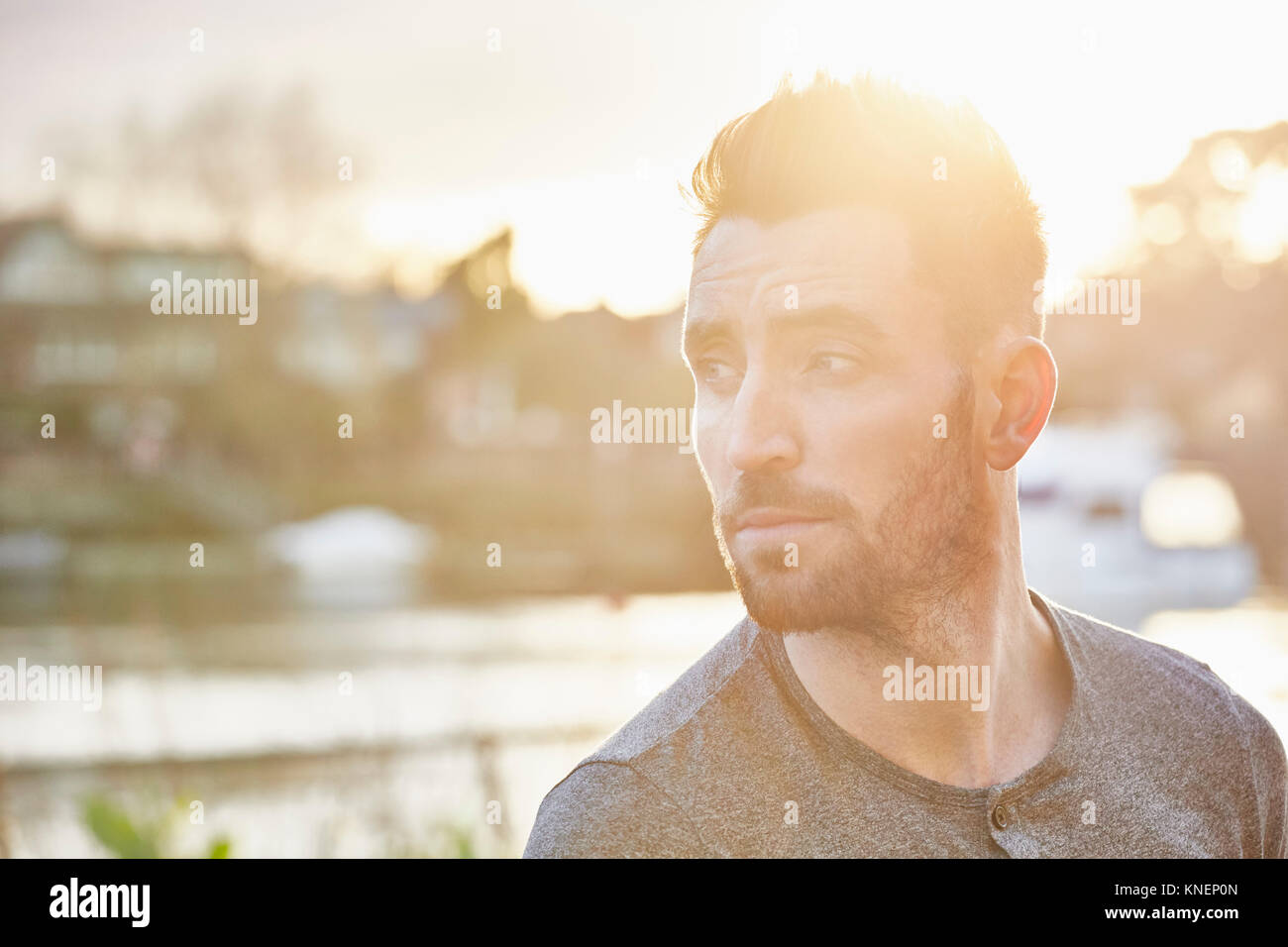 Hazy lens flare shot of bearded young man looking over his shoulder on ...