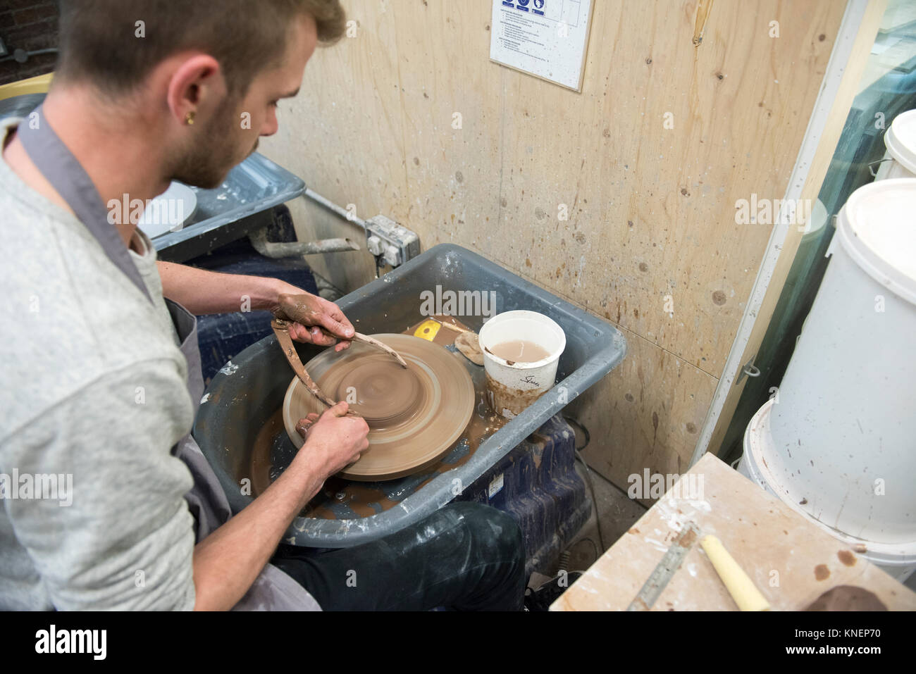 Man in art studio using pottery wheel Stock Photo - Alamy