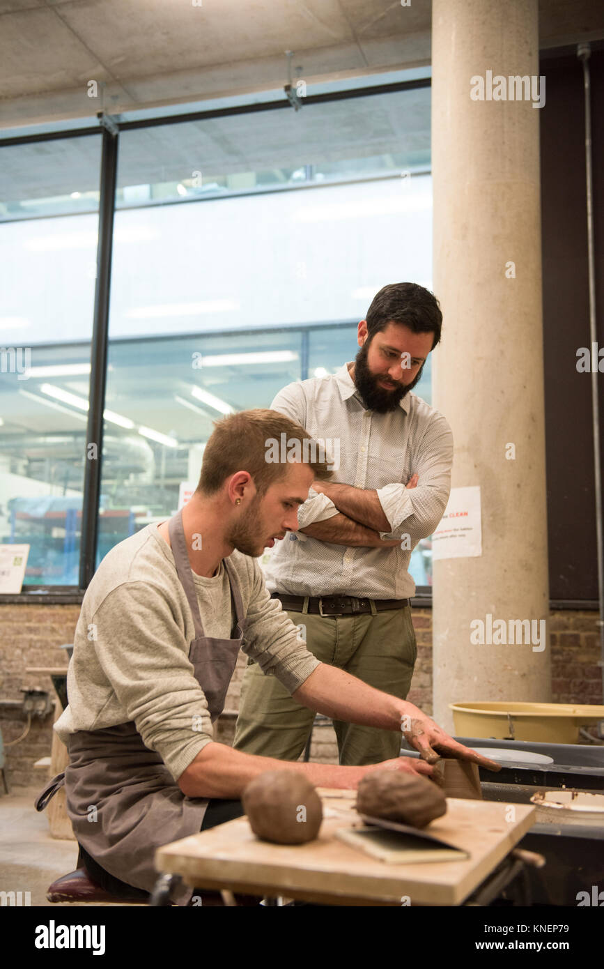 Tutor and student in art studio using pottery wheel Stock Photo - Alamy