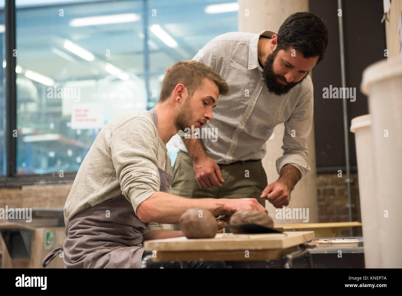 Tutor and student in art studio using pottery wheel Stock Photo - Alamy