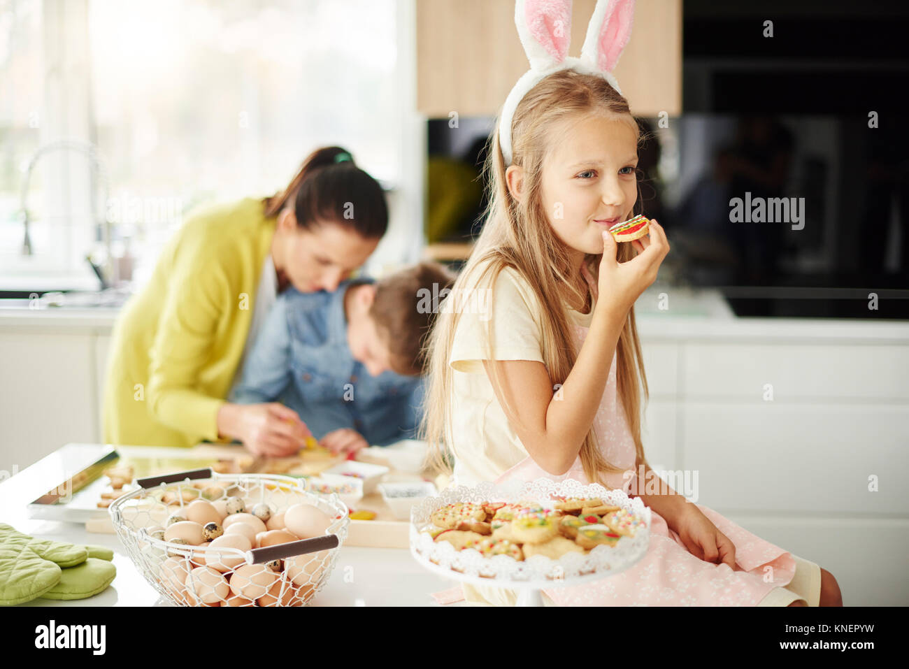 Girl eating easter biscuits on kitchen counter Stock Photo - Alamy
