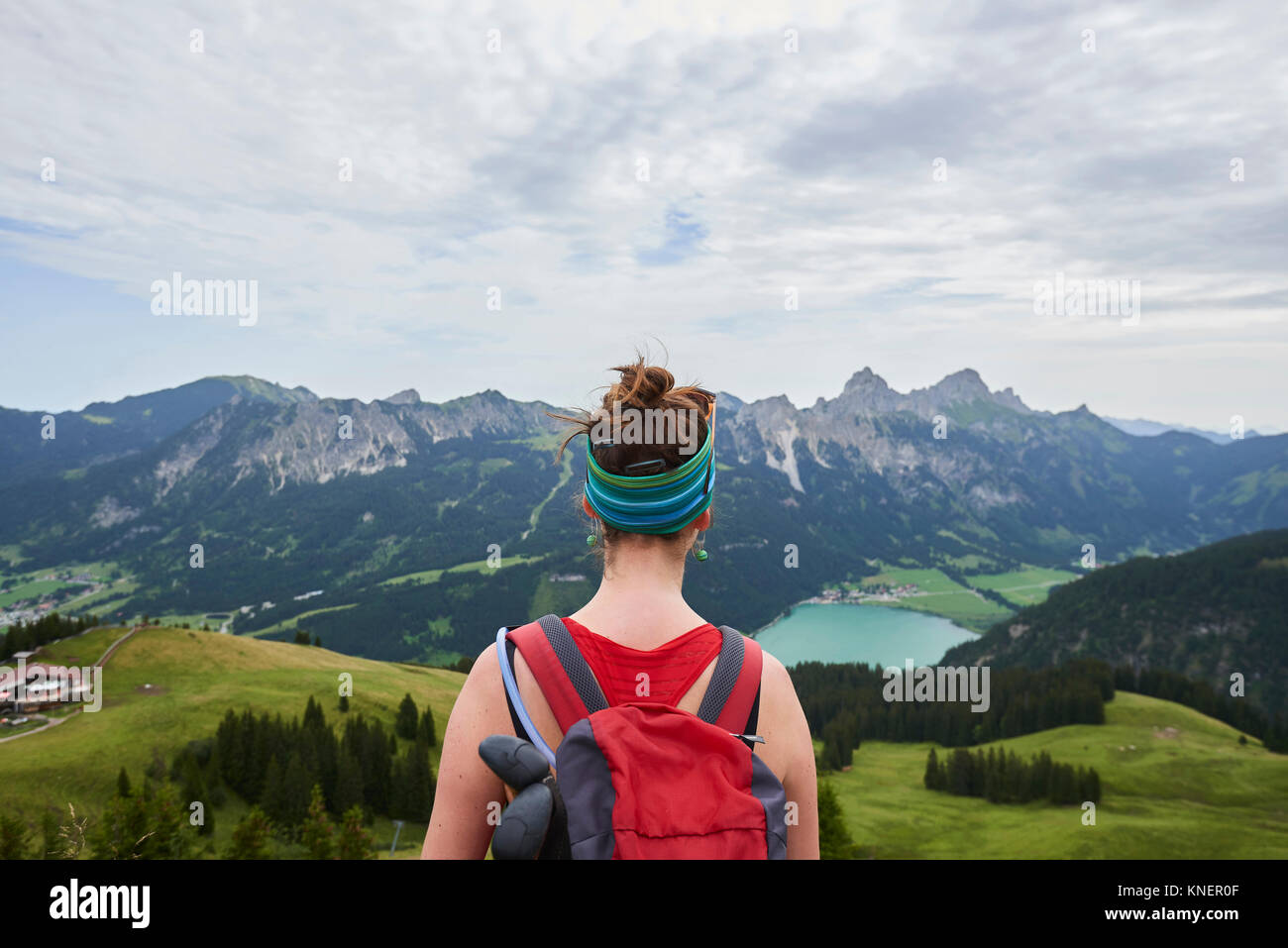 Rear view of female hiker looking out over valley in Tannheim mountains ...
