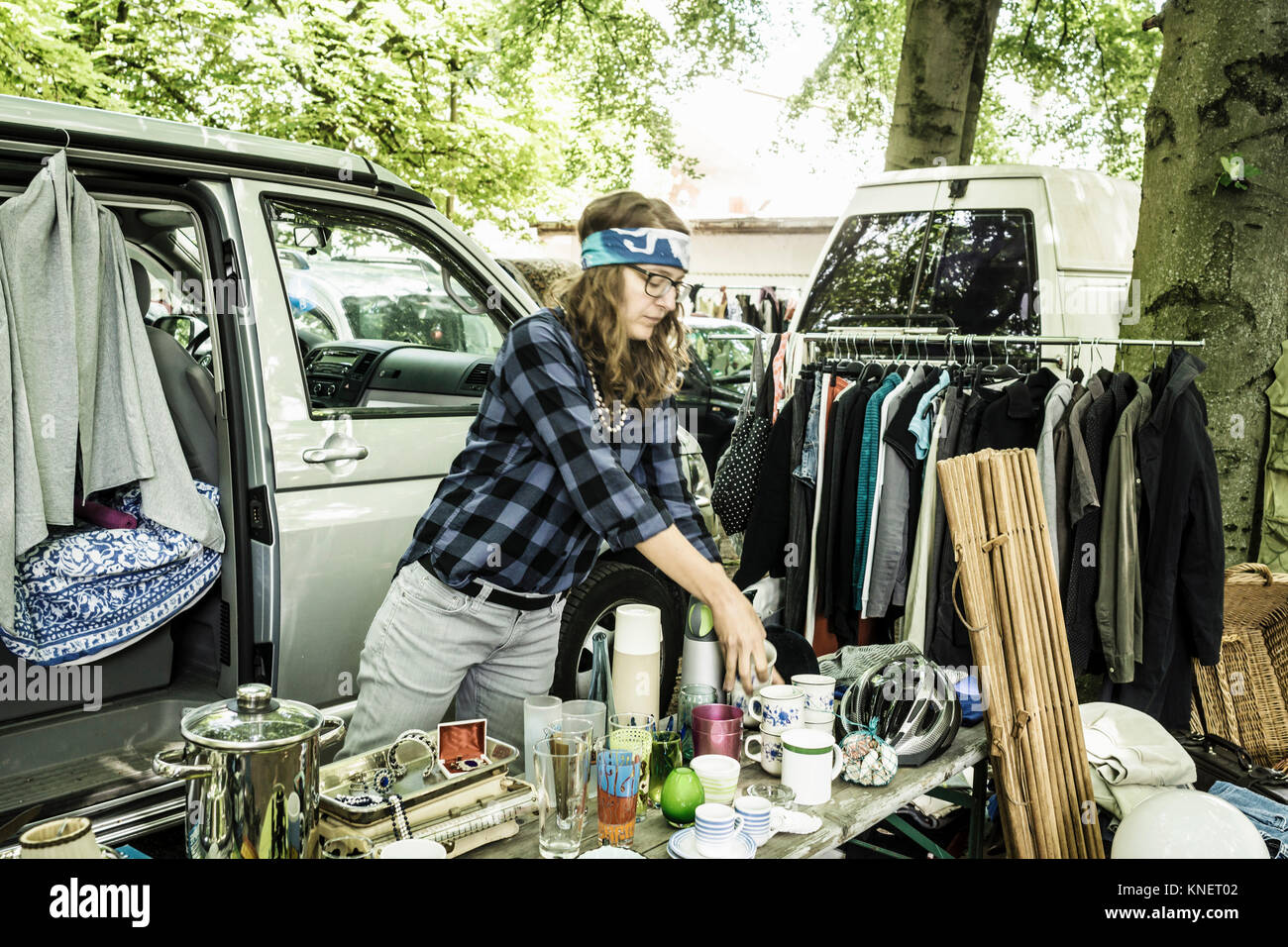 Female stall holder unpacking second hand cups on stall at forest flea ...