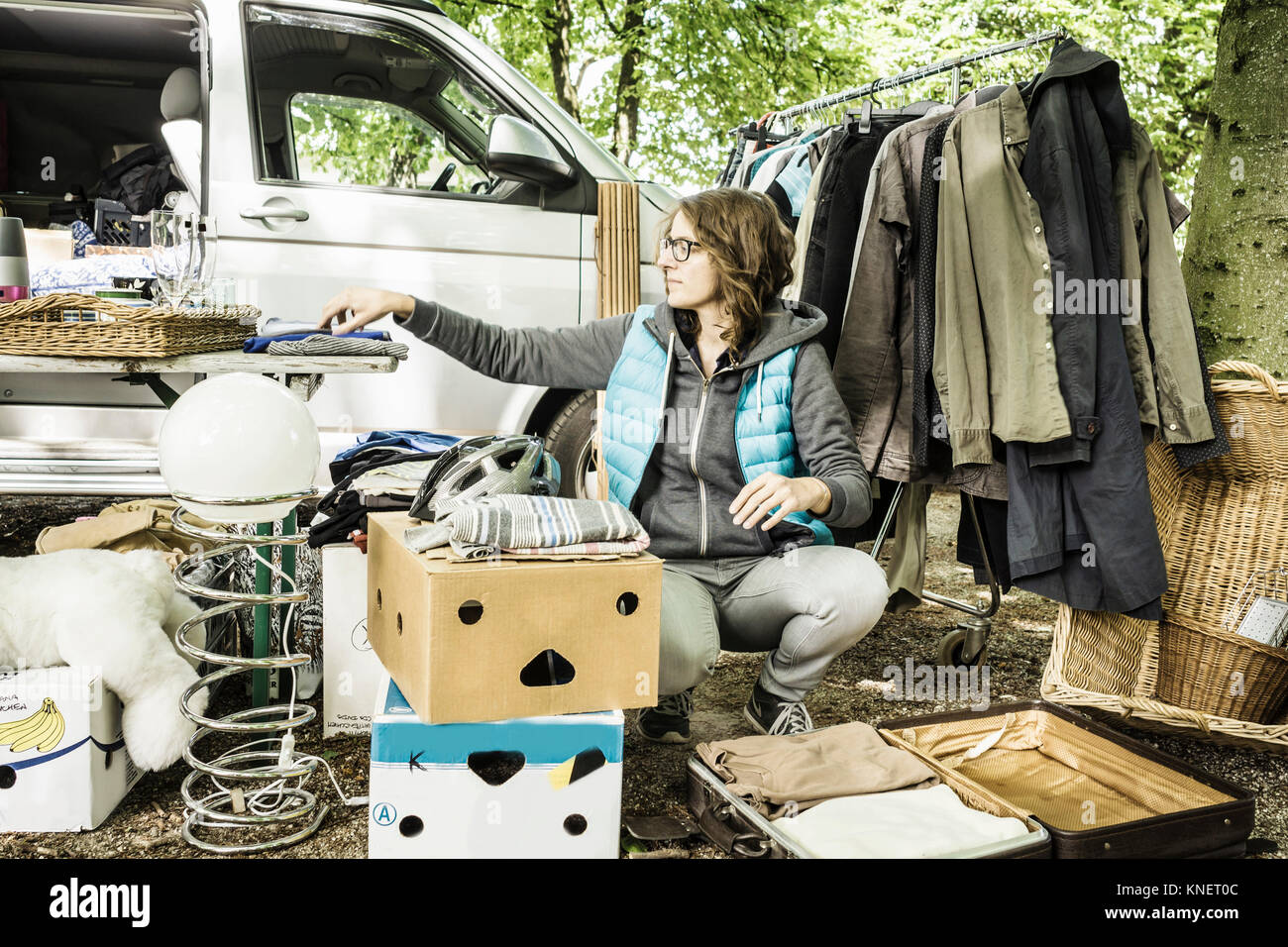 Female stall holder unpacking suitcase at second hand stall at forest ...