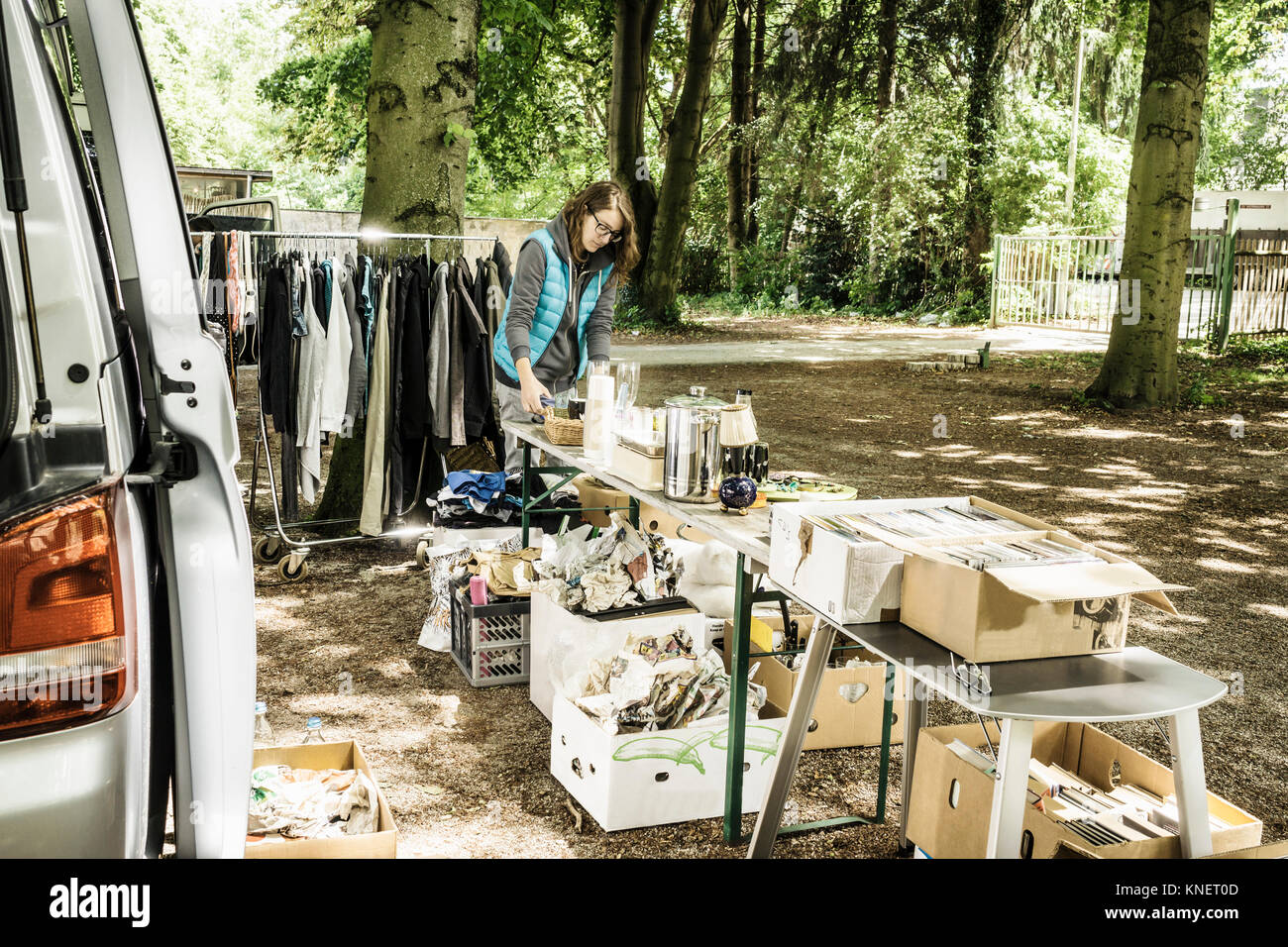 Female stall holder preparing at second hand stall at forest flea ...
