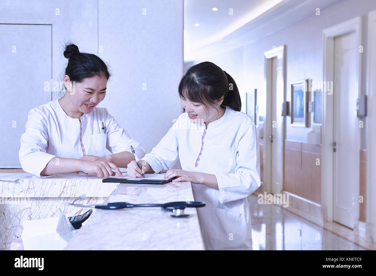 Medical professionals at hospital reception desk using digital tablet ...