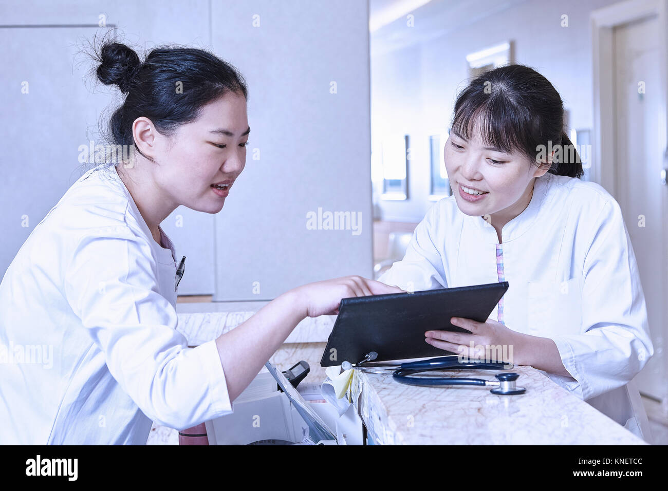 Medical professionals at hospital reception desk using digital tablet ...