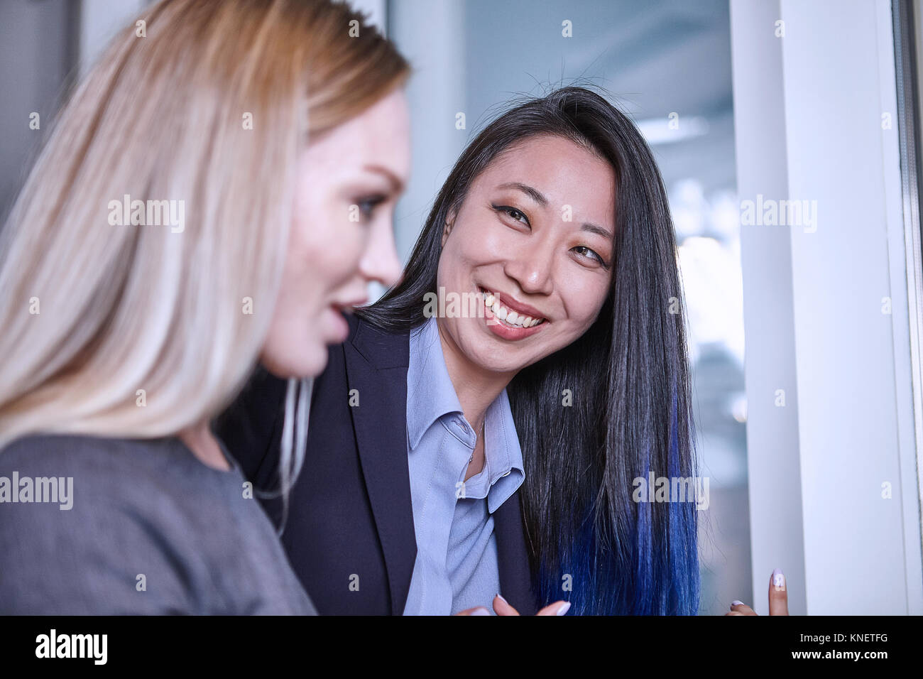 Woman looking at colleague smiling Stock Photo - Alamy