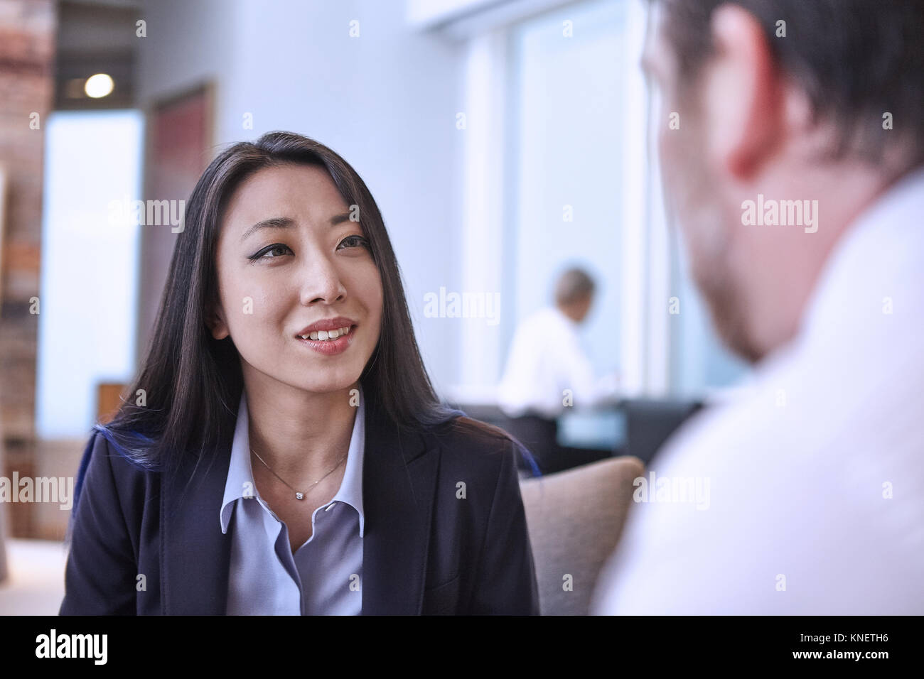 Woman looking at colleague smiling Stock Photo - Alamy
