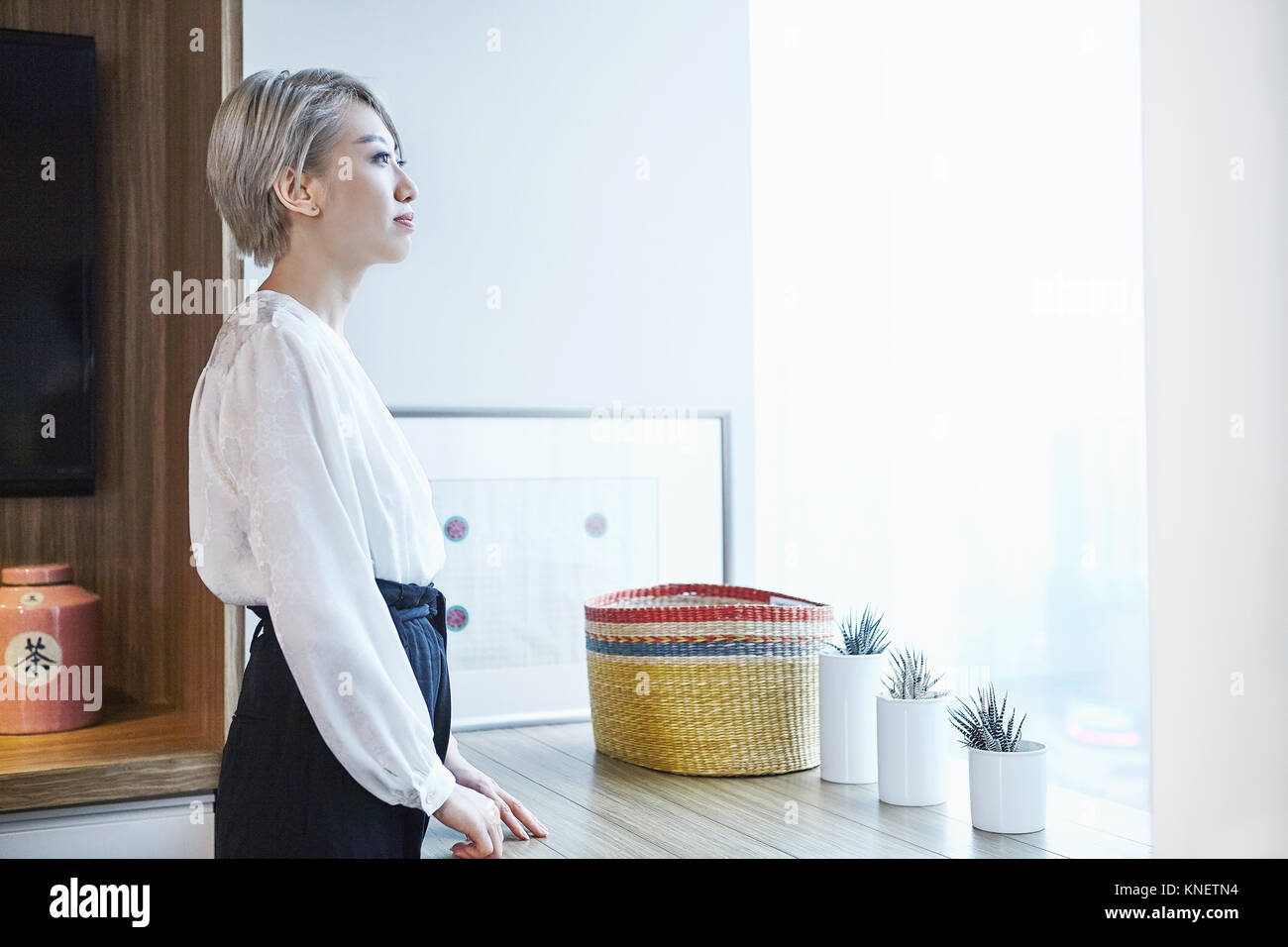 Side view of woman looking out of window pensively Stock Photo - Alamy