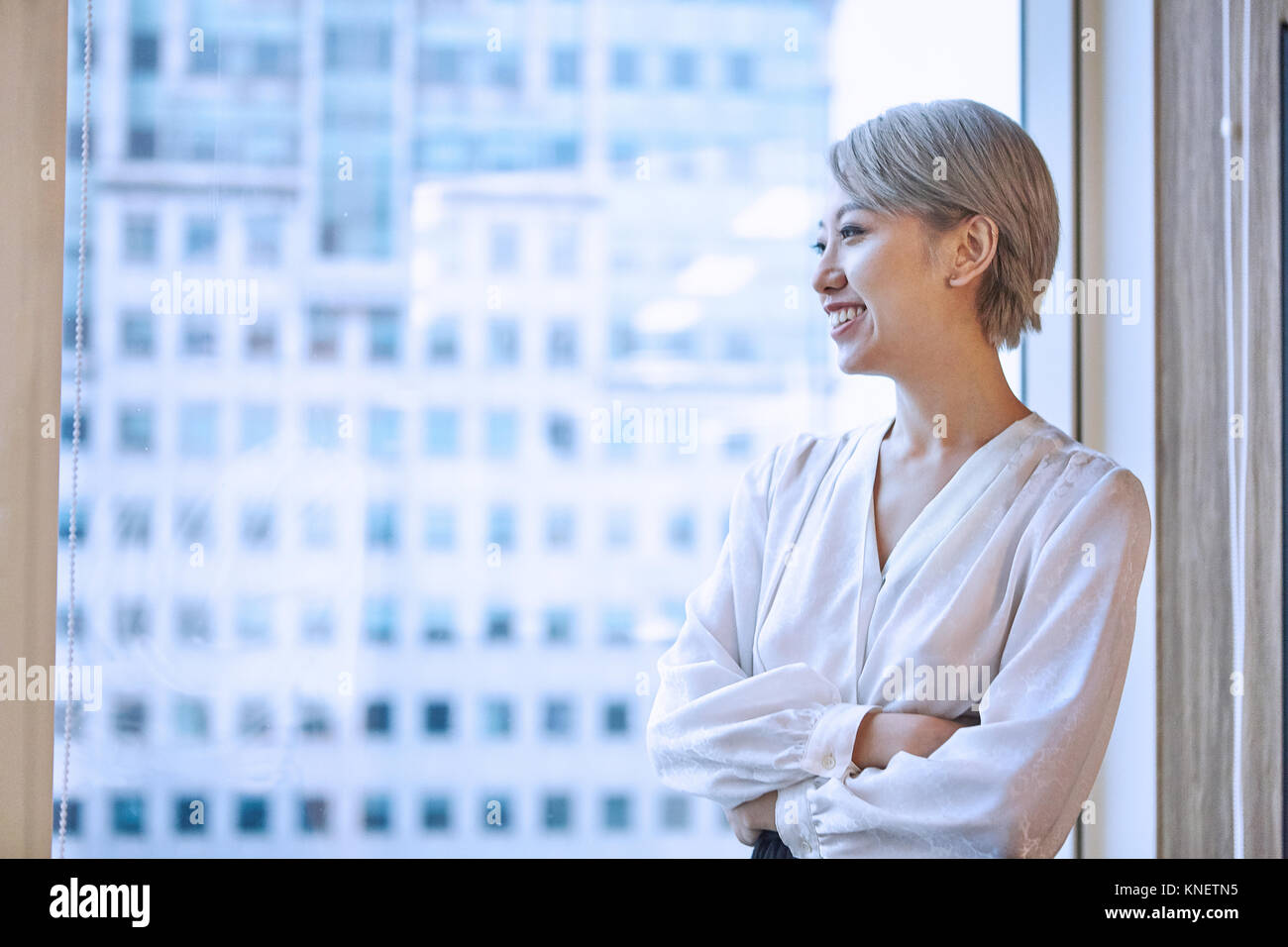 Portrait of businesswoman looking out of window smiling Stock Photo - Alamy