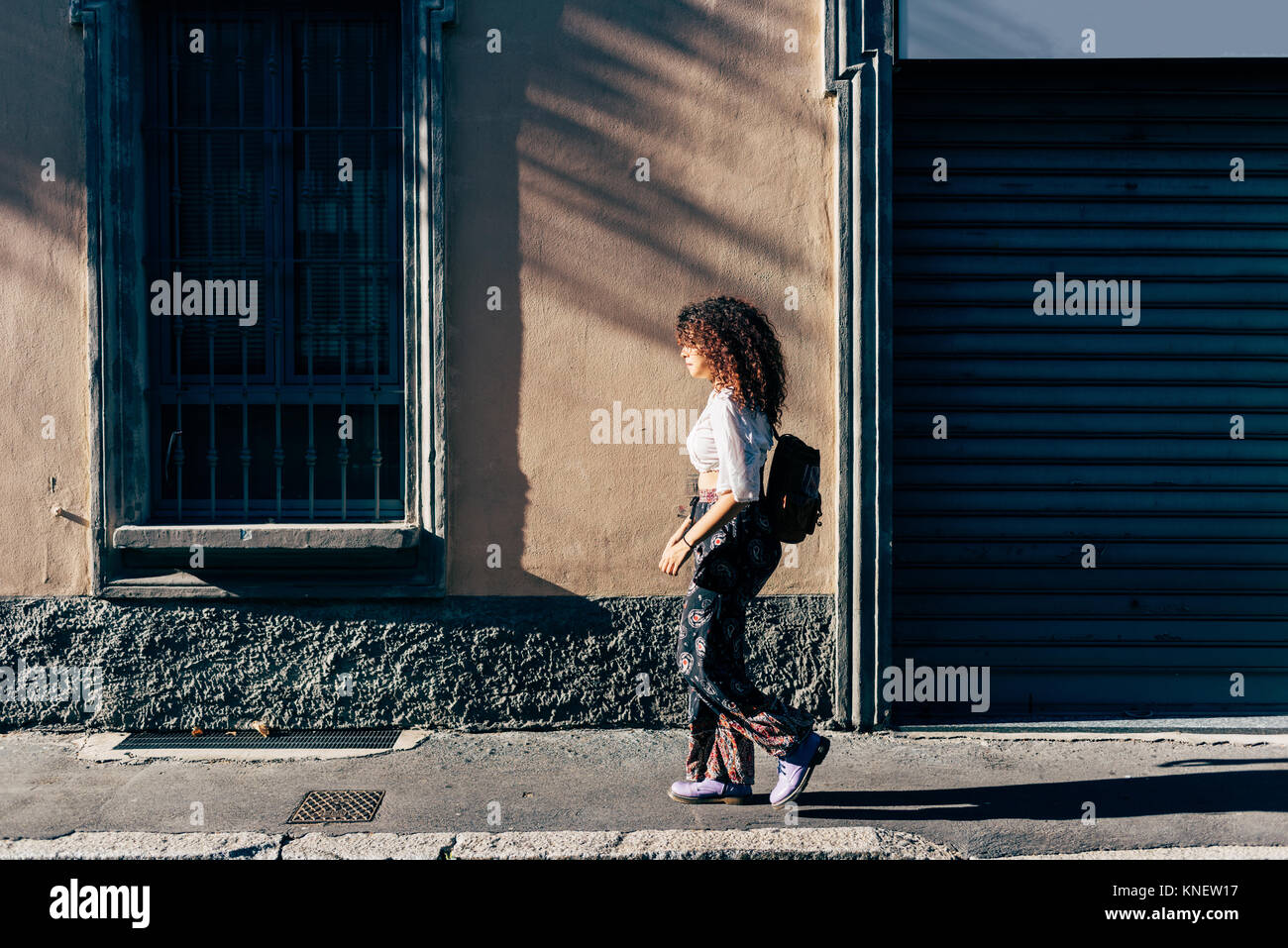 Woman passing roller shutters of closed shop, Milan, Italy Stock Photo ...