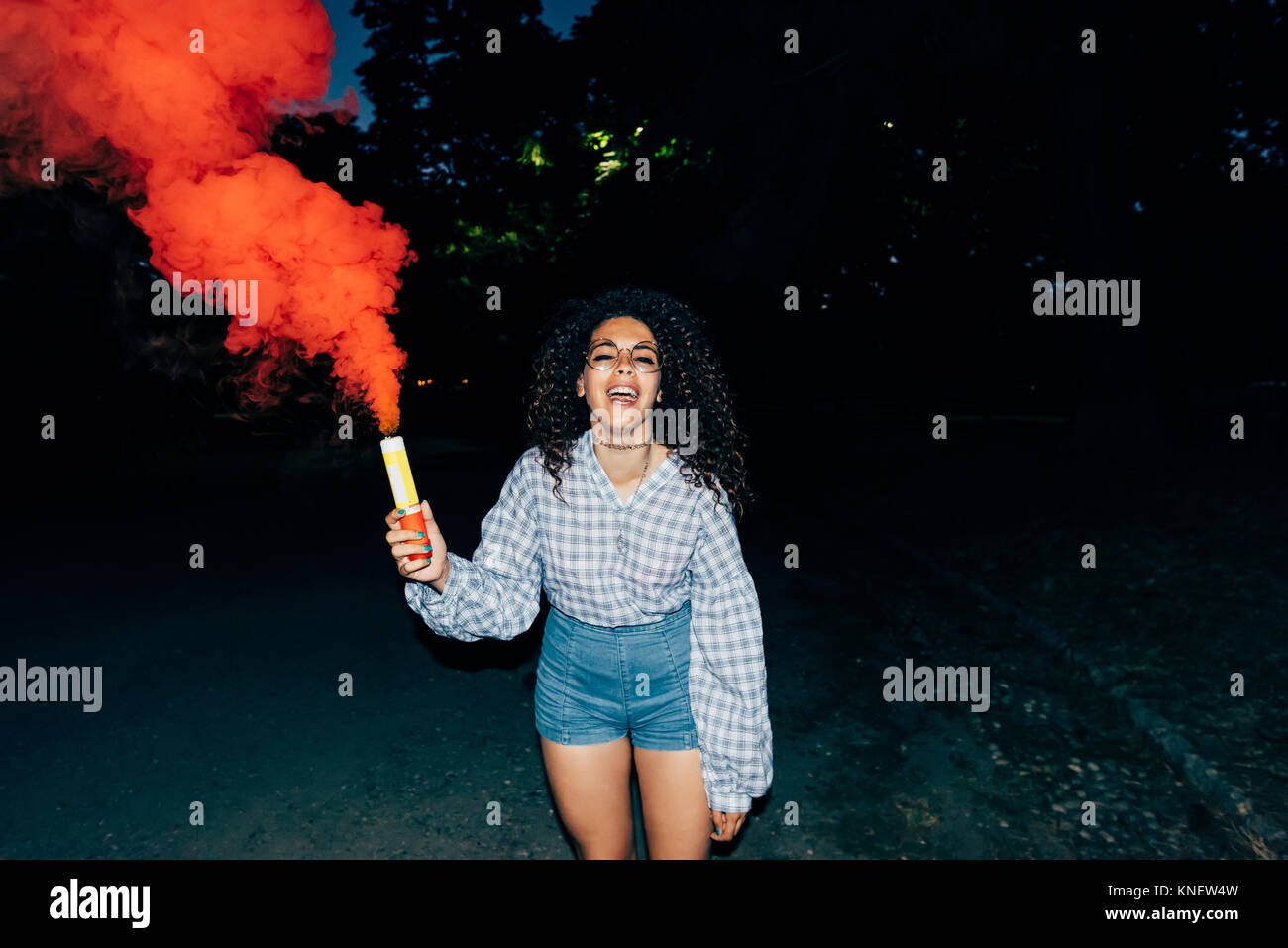 Woman holding flare in park at night Stock Photo - Alamy