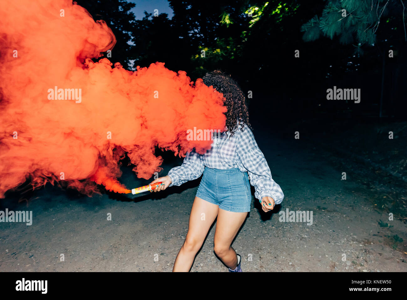 Woman holding flare in park at night Stock Photo - Alamy