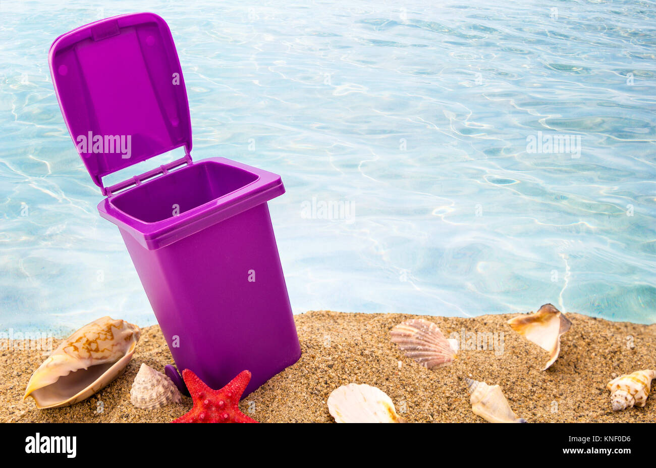 Trash can on clean sand and shells with seascape background Stock Photo ...